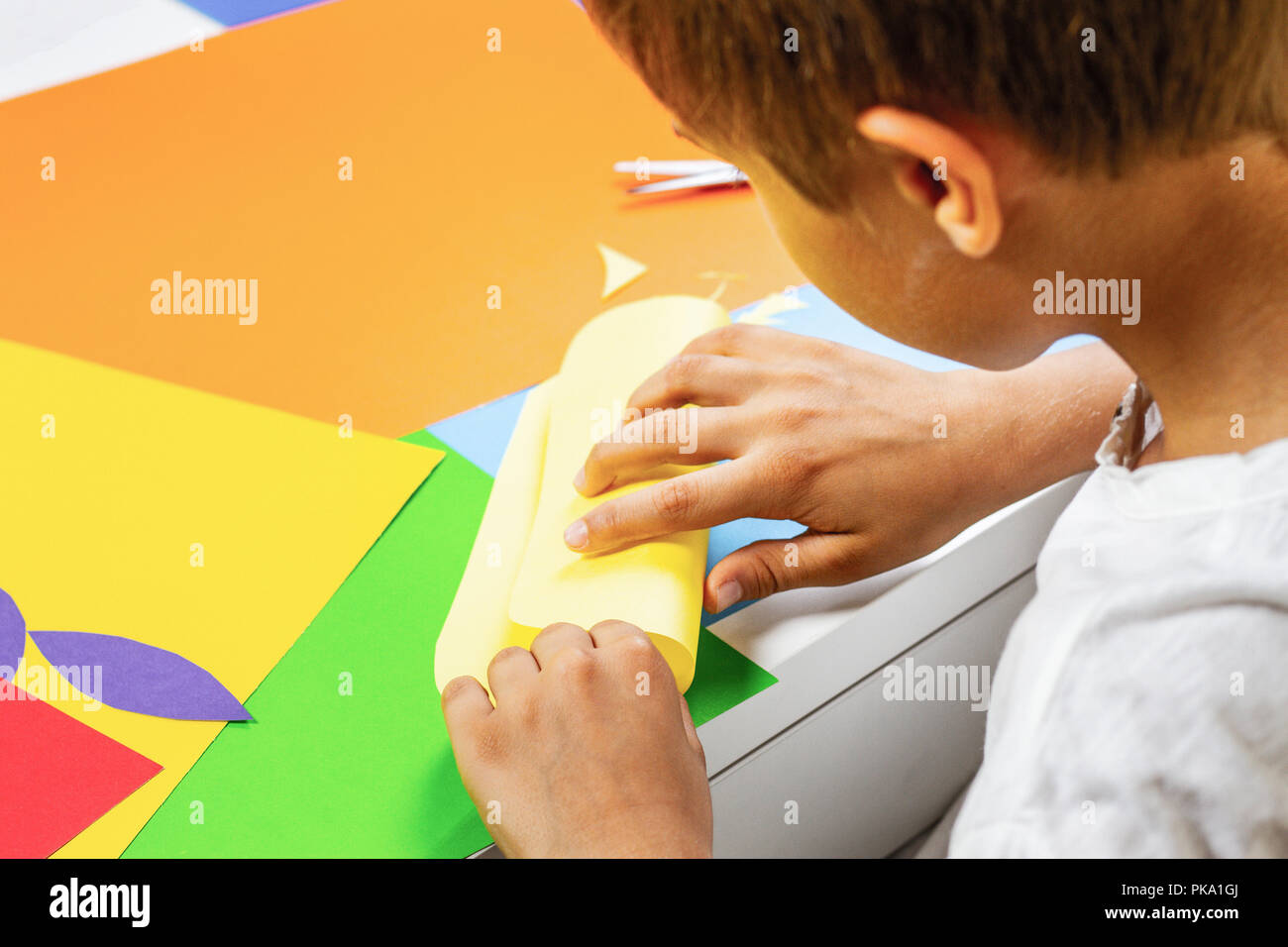 Child making greeting card with colored paper at the table Stock Photo ...
