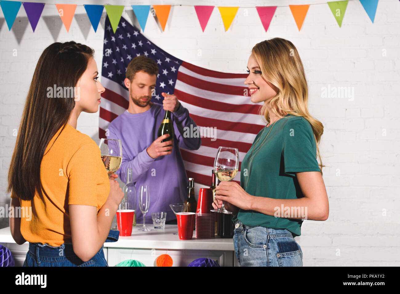 beautiful young women holding glasses of wine and looking at each other ...