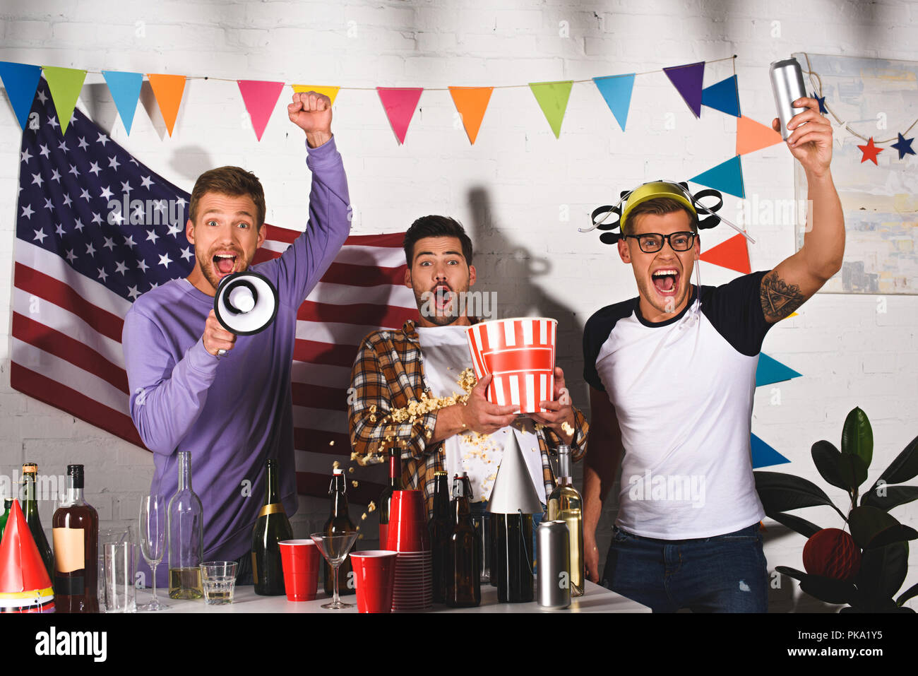 excited young men having fun and screaming at camera at home party ...