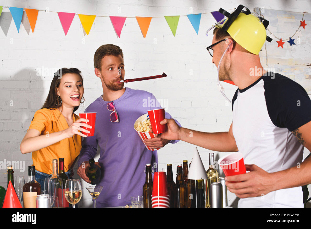 happy young people drinking alcohol and eating popcorn at home party ...