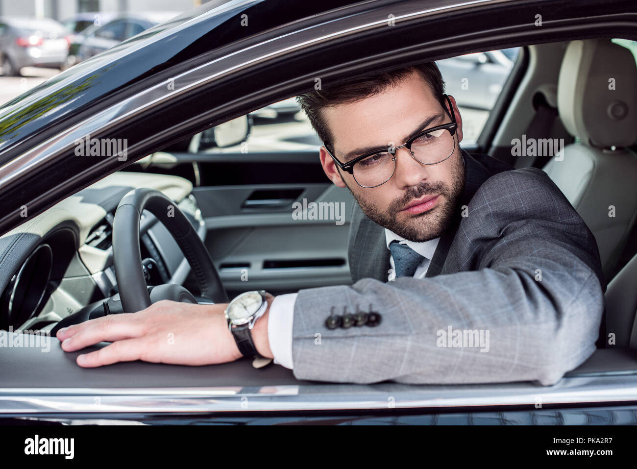 side view of pensive businessman in eyeglasses looking away while ...