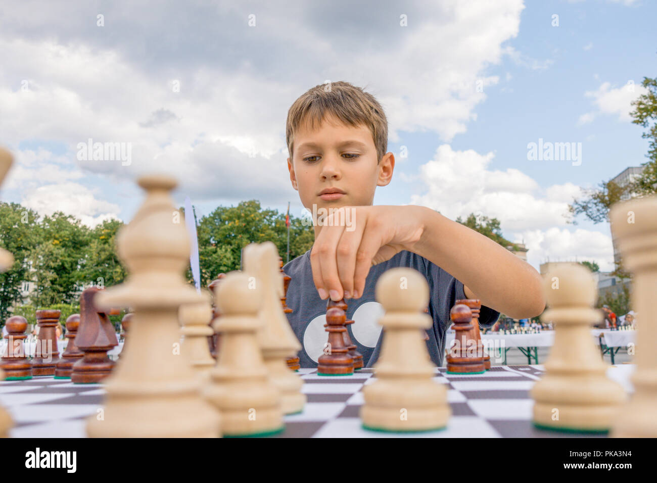 Kid playing chess at chessboard outdoors. Boy thinking hard on chess ...