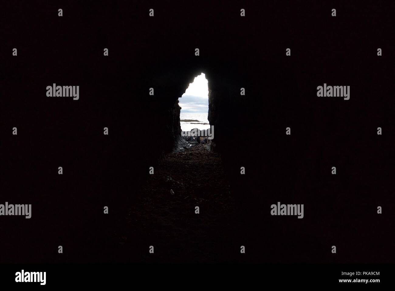 Looking out at the sea from a sea cave along a rocky beach in Scotland ...