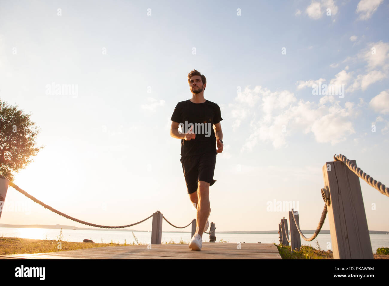 Full length shot of healthy young man running on the promenade. Male ...