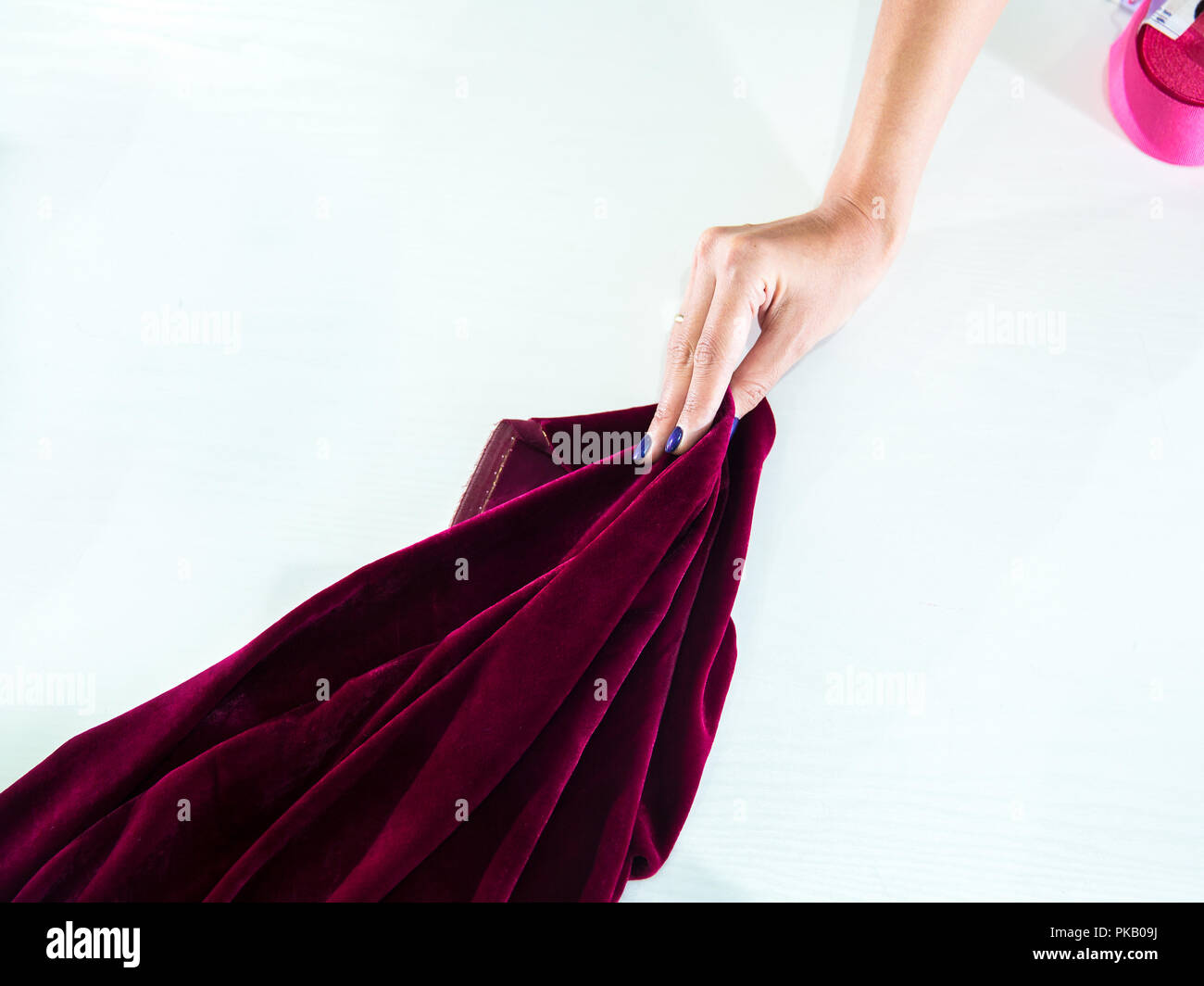 A woman's hand pulls the cloth on the table, a red velvet fabric, on a ...