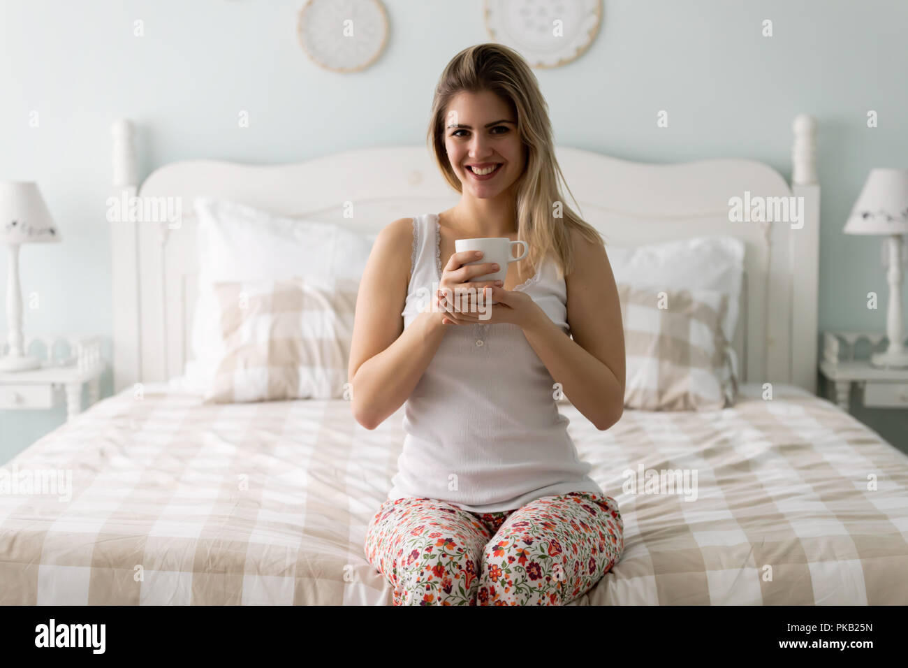 Young beautiful woman sitting on bed at home Stock Photo - Alamy