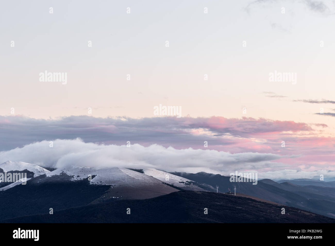 Mountain range covered by snow at sunset, with warm, purple shades ...