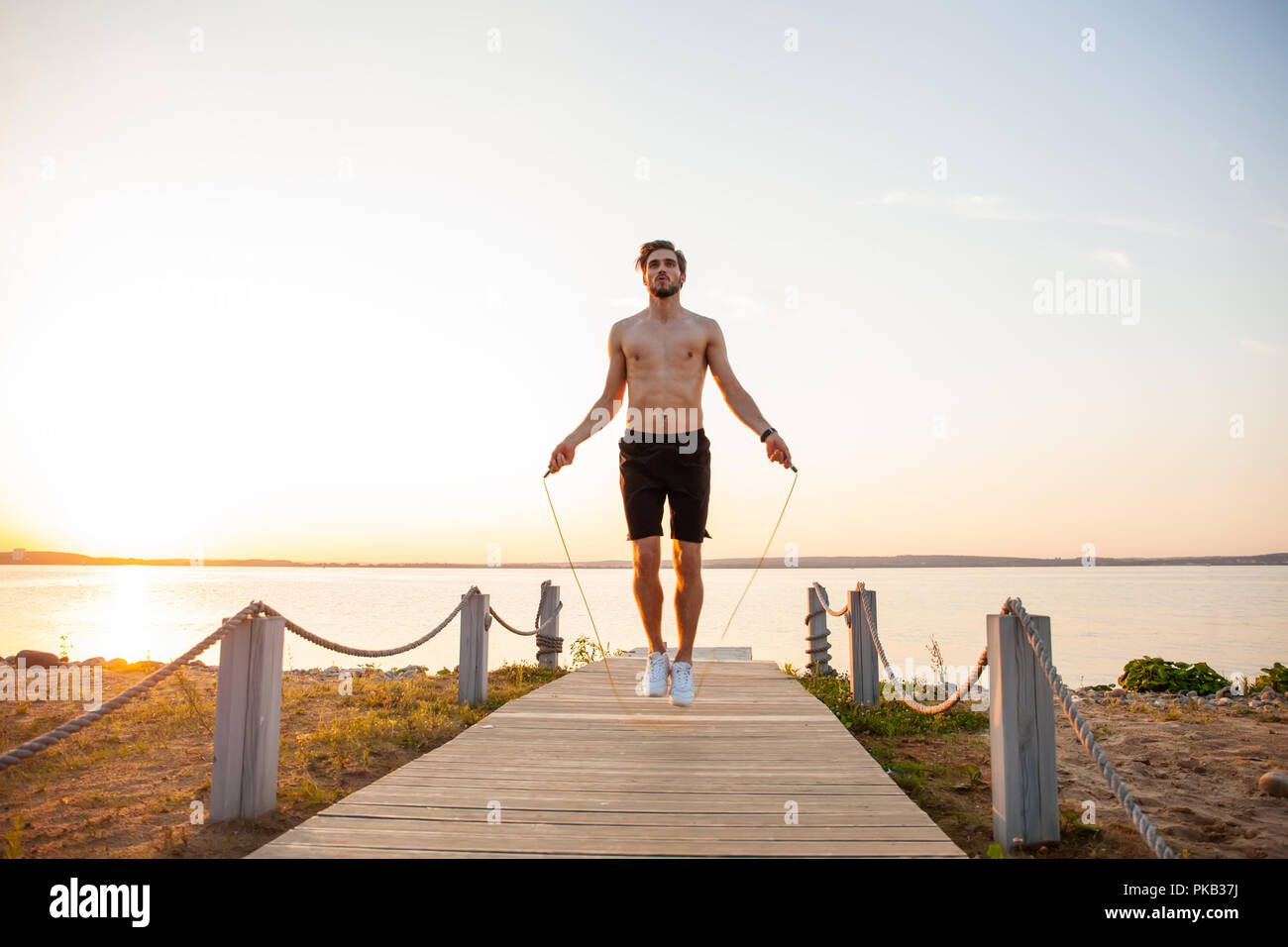 Portrait of muscular young man exercising with jumping rope Stock Photo ...