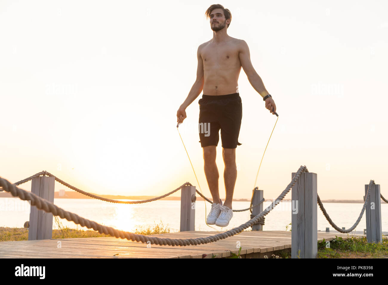 Portrait of muscular young man exercising with jumping rope Stock Photo ...
