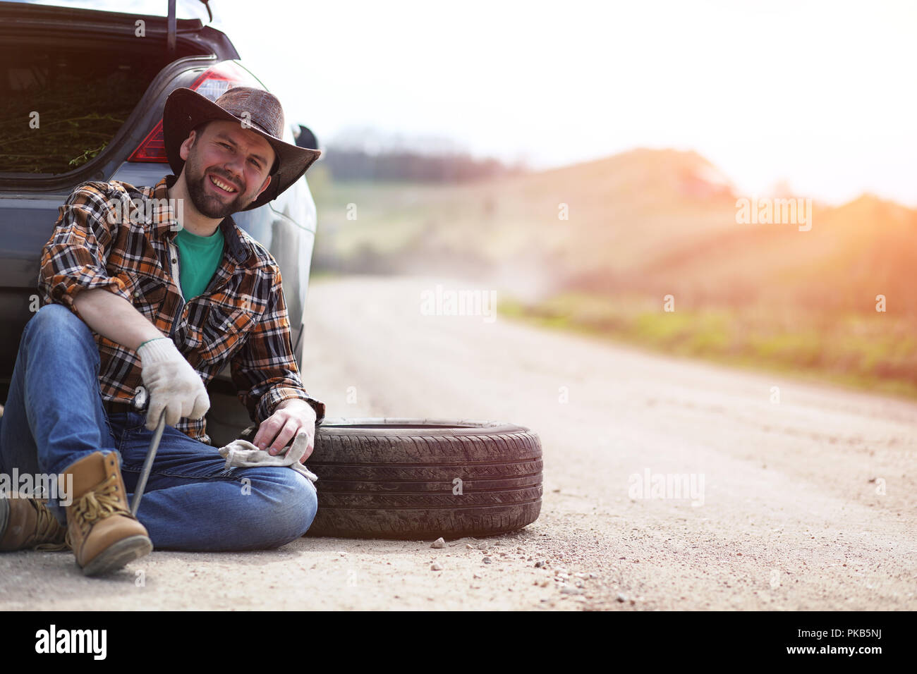 Man is sitting on the road by the car Stock Photo - Alamy