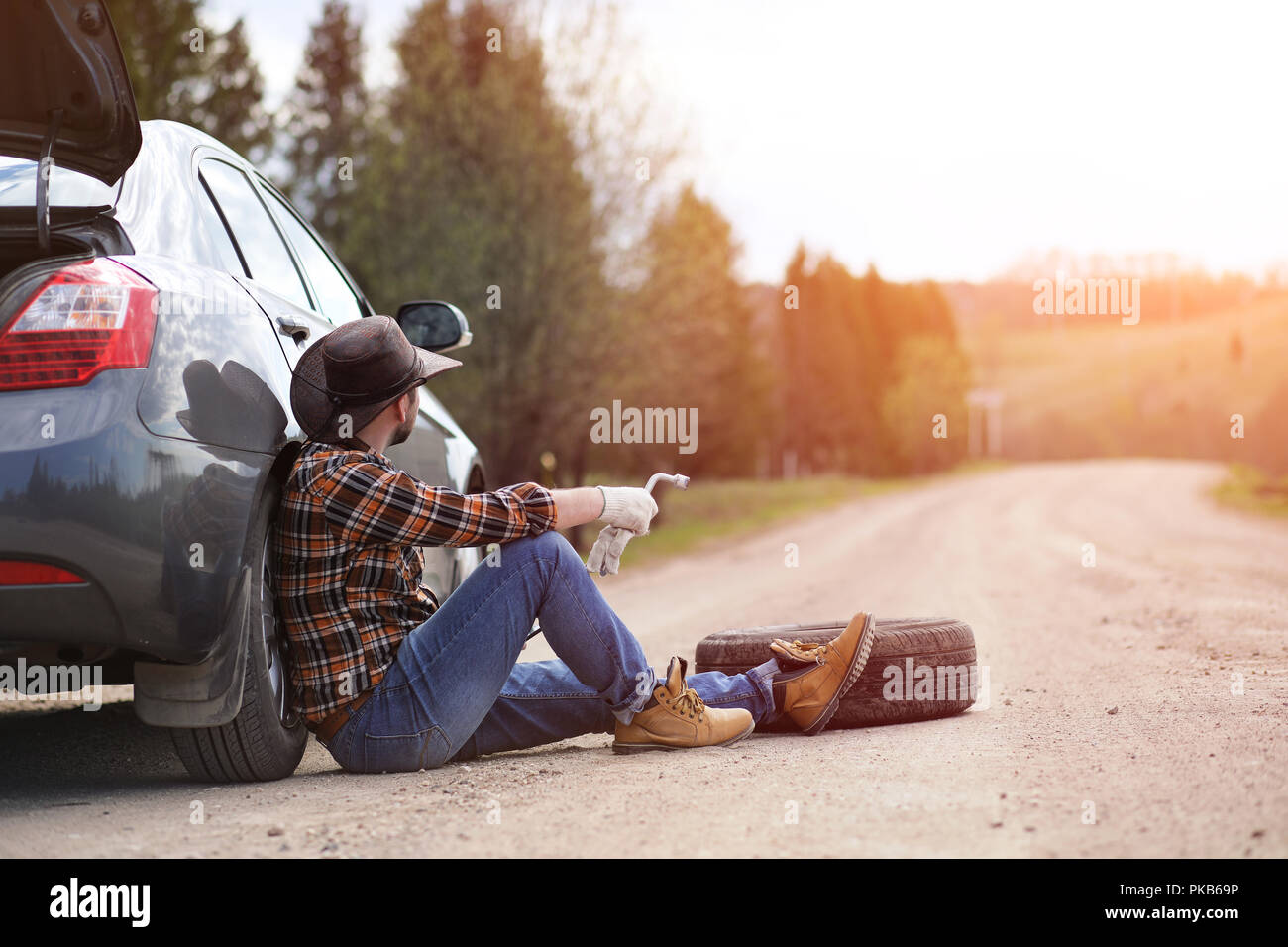 Man is sitting on the road by the car Stock Photo - Alamy