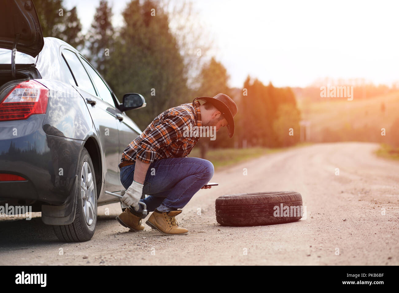Man is sitting on the road by the car Stock Photo - Alamy