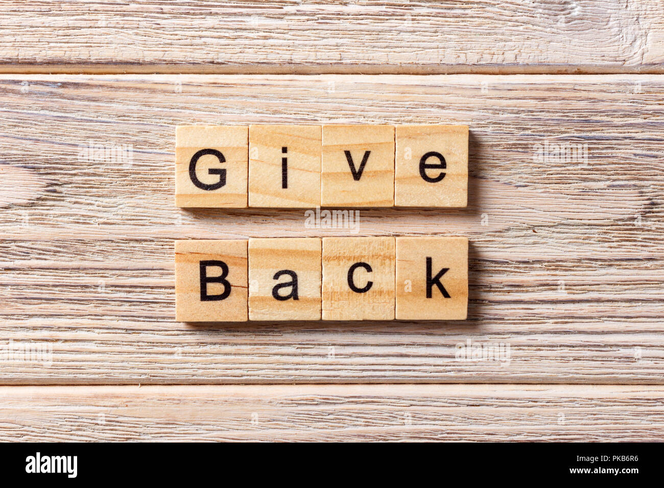 Give Back word written on wood block. Give Back text on table, concept ...
