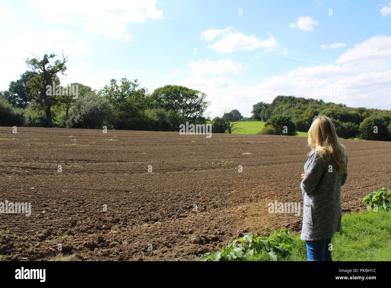 Girl looking over rural field Stock Photo - Alamy