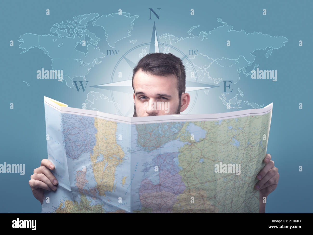 Handsome young man holding a map with a world map and a compass behind ...