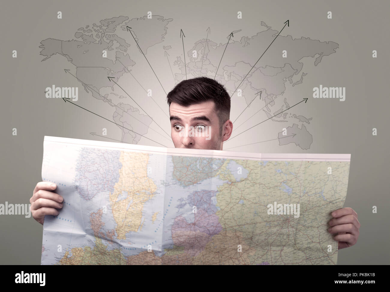 Handsome young man holding a map with world map and arrows behind him ...