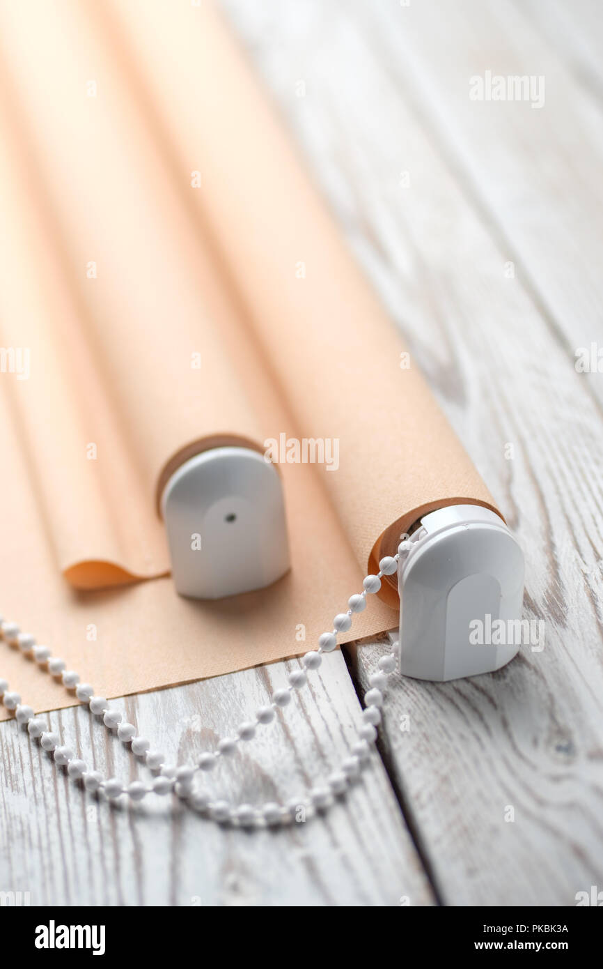 The rolled beige shutters is on a wooden surface. Beige blinds lie on ...