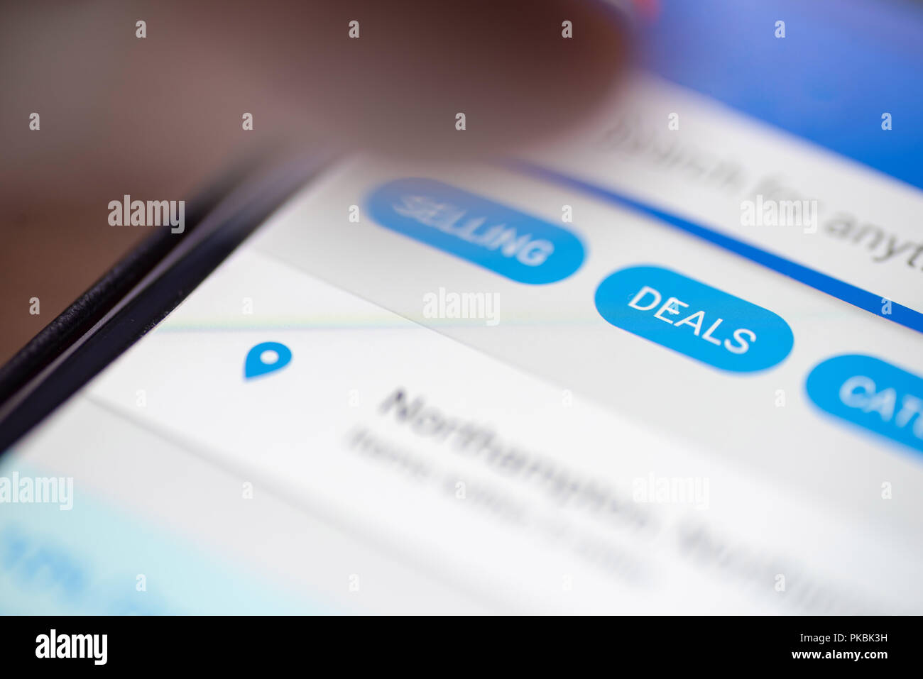 Human finger thumb over Deals button icon on shopping app on smartphone ...