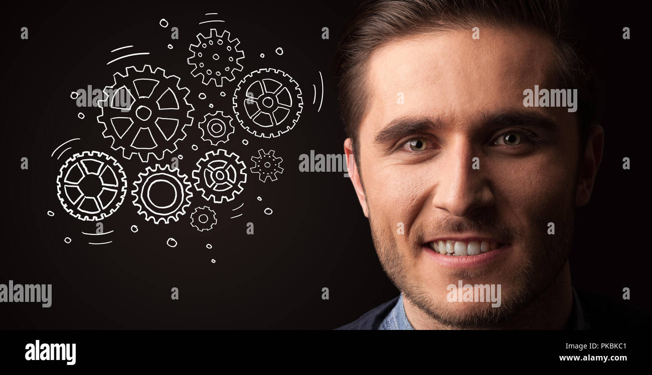 Portrait of a young businessman with rotating gears next to him on a ...