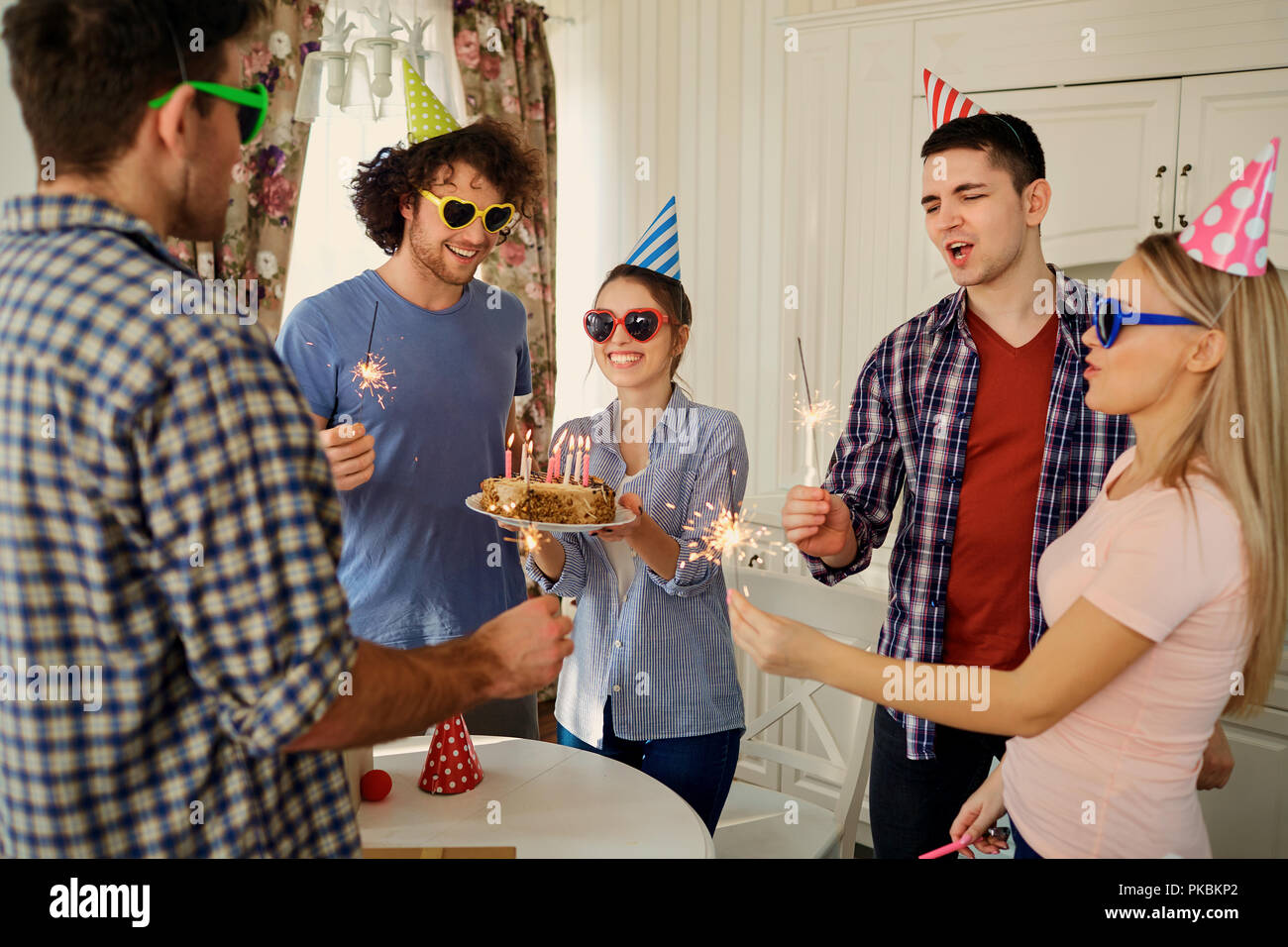 Friends with cake celebrating birthday at a party Stock Photo - Alamy
