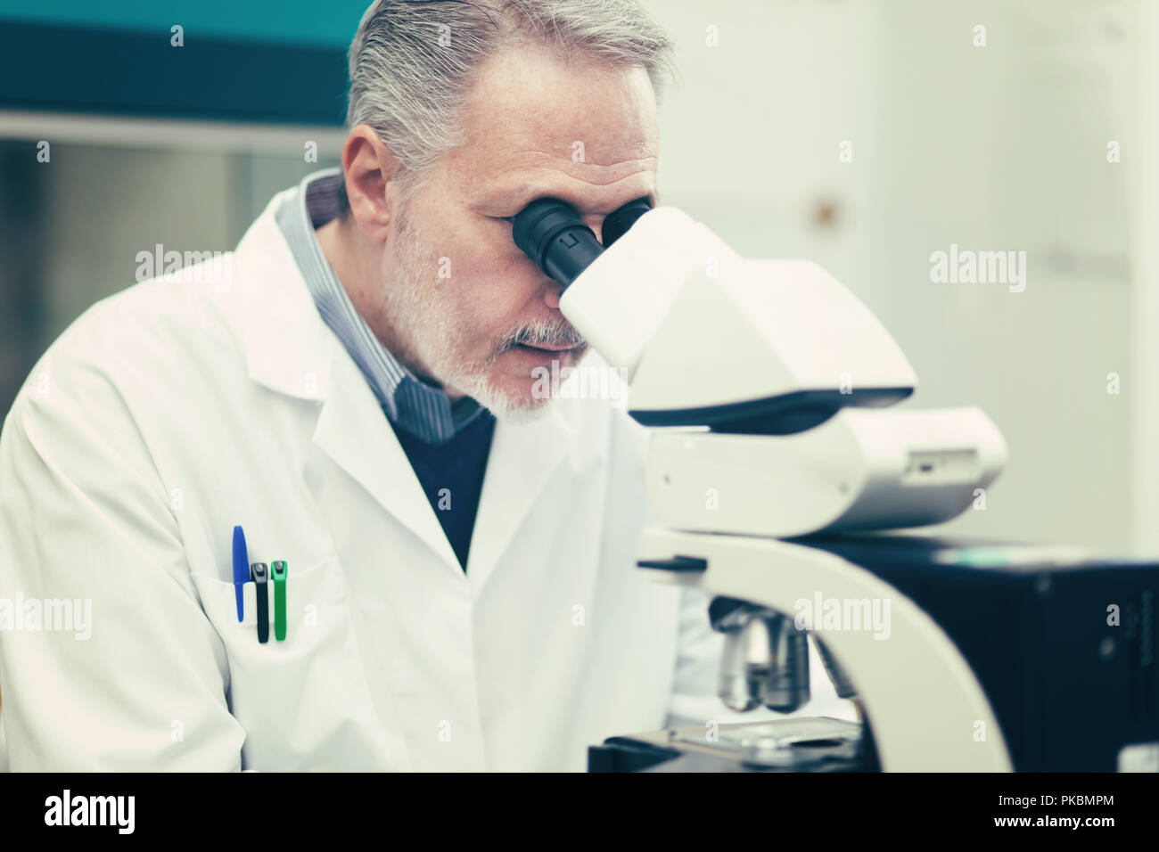 Scientist conducting research looking through microscope Stock Photo ...