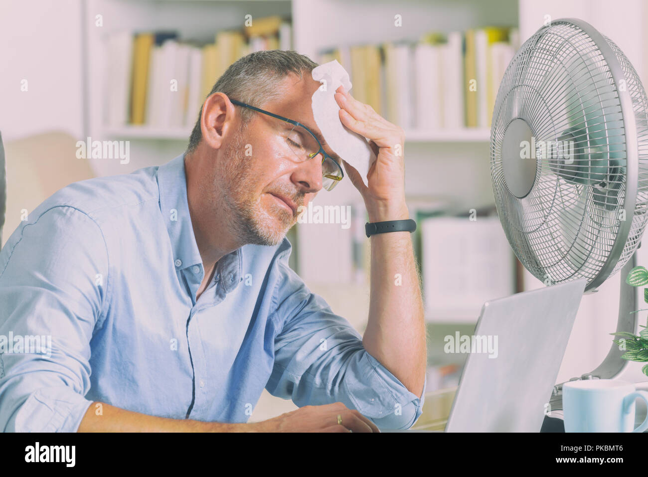 Man suffers from heat while working in the office and tries to cool off ...