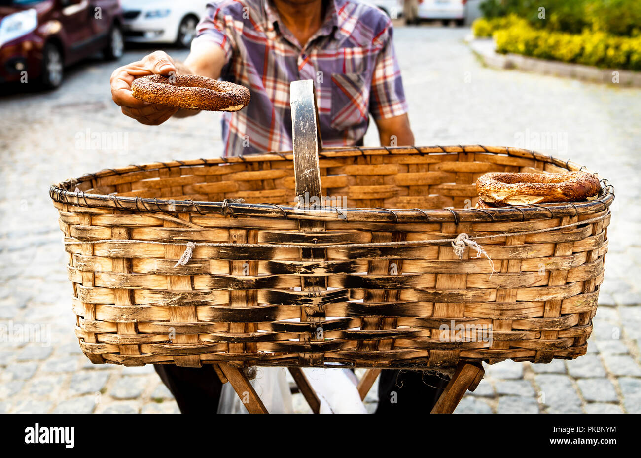 Street vendor selling simit (bread with sesame seeds) in basket and ...