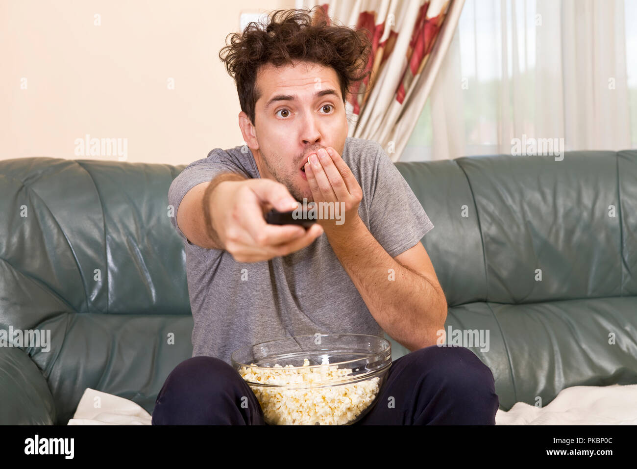 Lazy man with the remote on the couch Stock Photo - Alamy