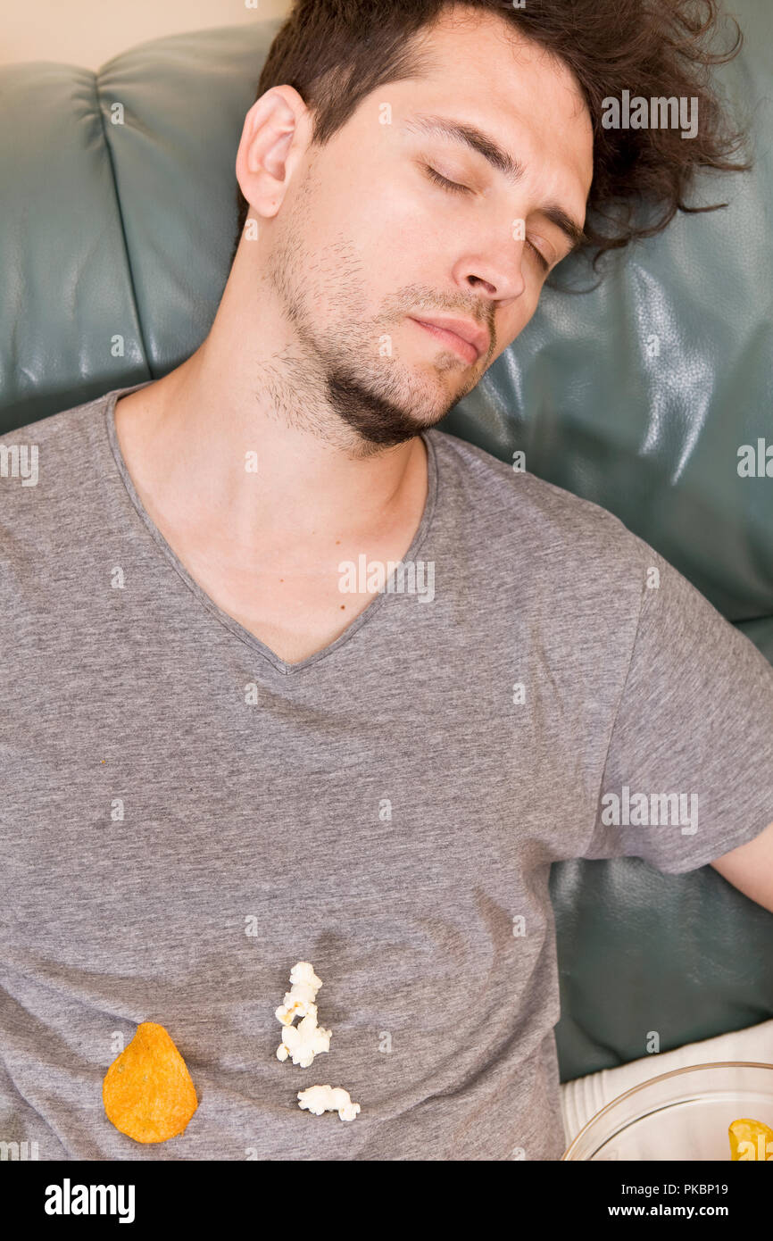 A man sleeping on a couch in a mess of junk food Stock Photo - Alamy