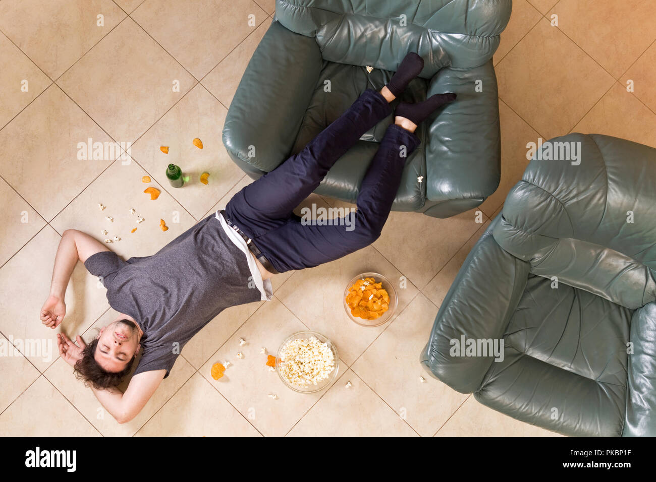 Young man after heavy partying at home. A lot of beer and junk food ...