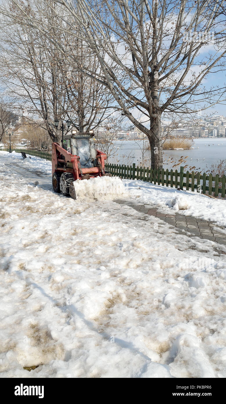 Mini track removes snow from the sidewalk Stock Photo - Alamy