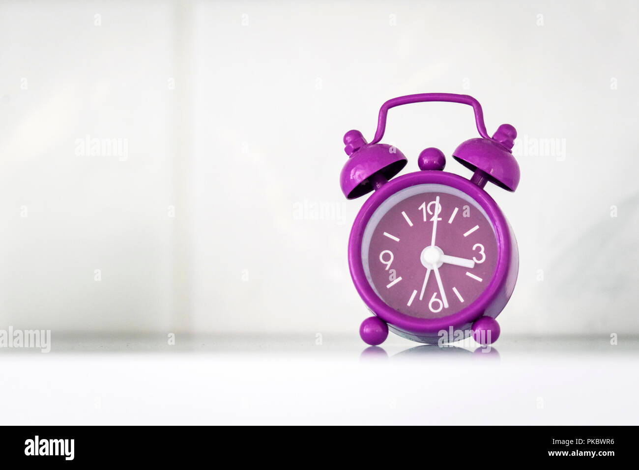 Purple alarm clock in a bright room showing the time Stock Photo - Alamy