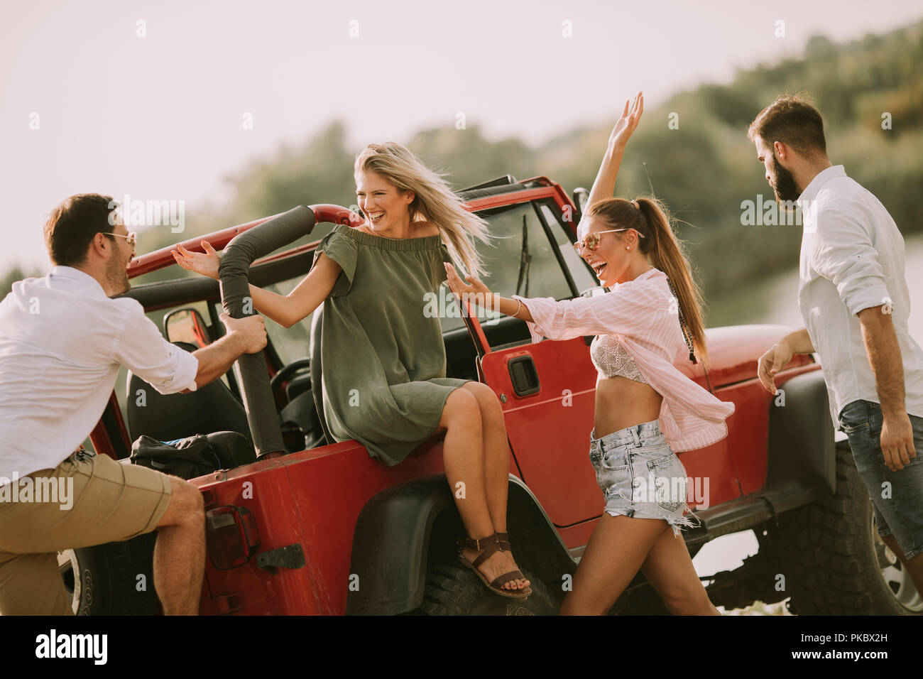 Four young people having fun in convertible car by river Stock Photo ...