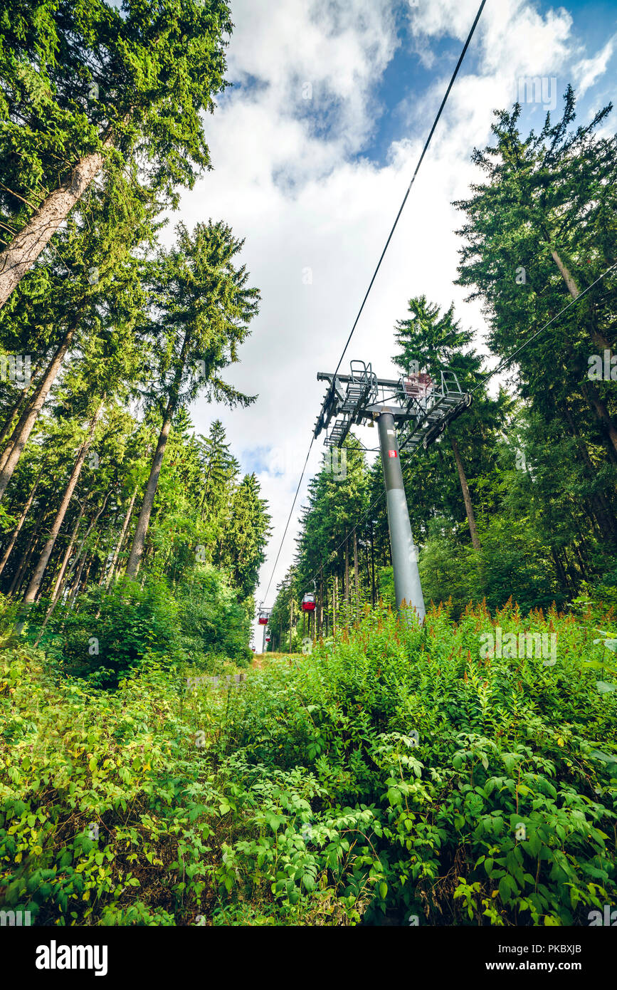 Mountain lift on a green forest with tall pine trees in the summer ...