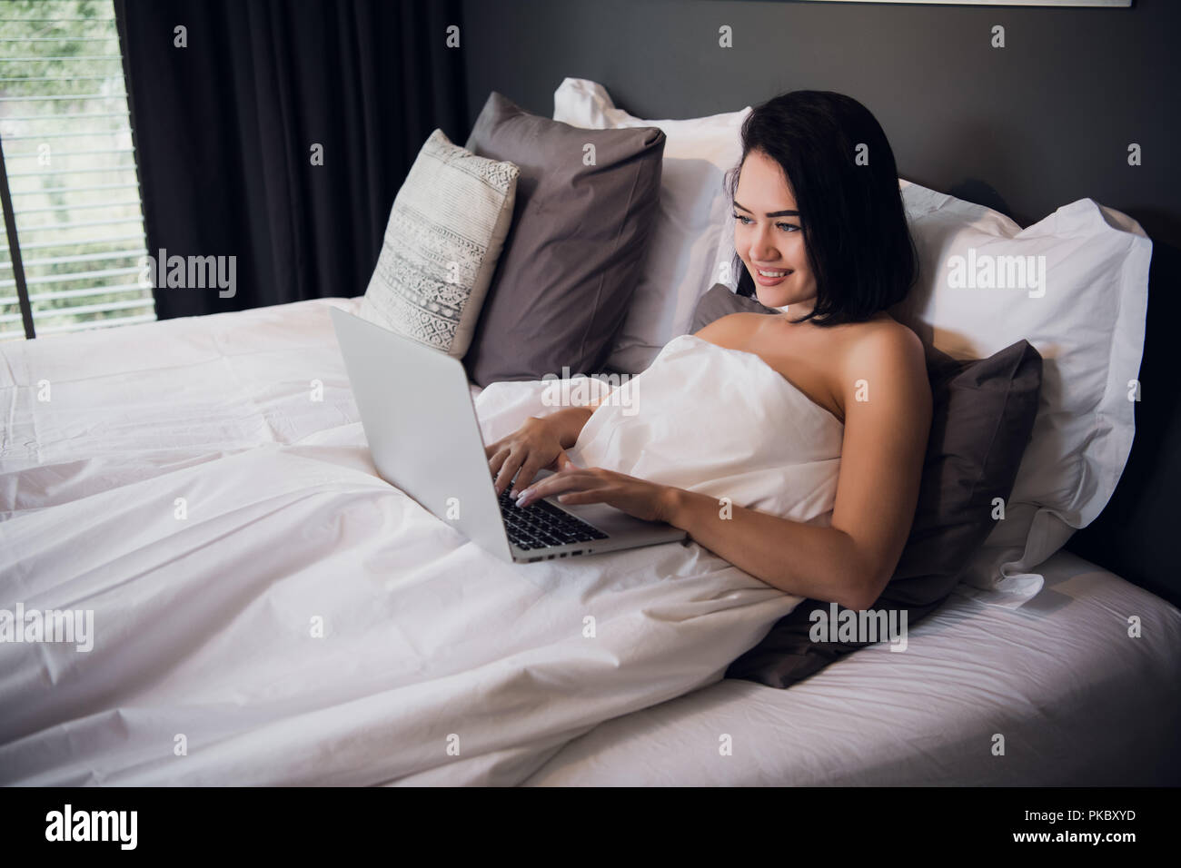Portrait of beautiful young woman with laptop on bed Stock Photo - Alamy