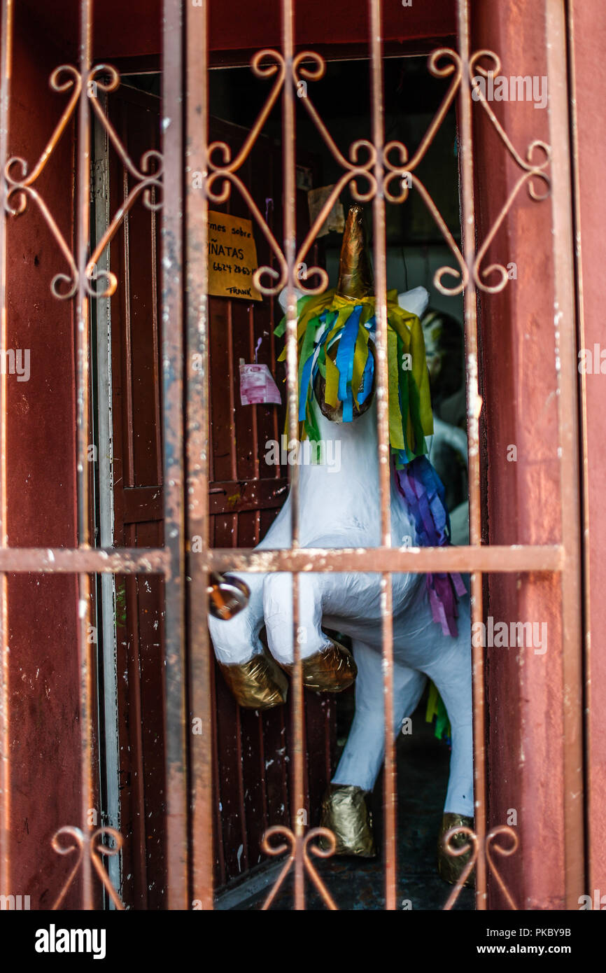 paper piñata in the shape of a unicorn enclosed behind the steel bars ...