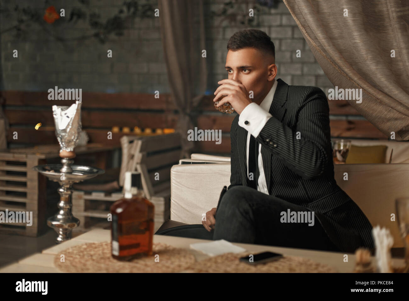 Handsome young man in a suit drinking whiskey in the modern bar Stock Photo - Alamy