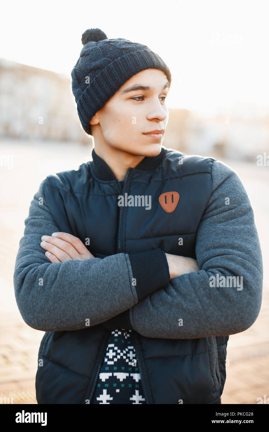 Stylish young man in knitted hat, sweater and jacket on the background ...