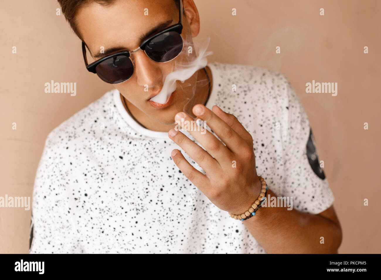 Young handsome guy smoking a cigarette. Clouds of smoke Stock Photo - Alamy