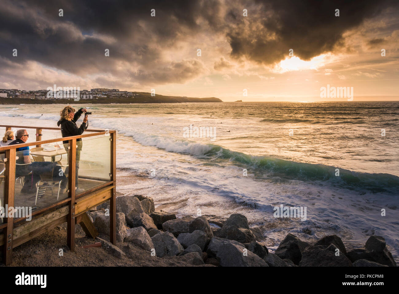 A holidaymaker taking a photograph during a sunset at Fistral Beach in ...