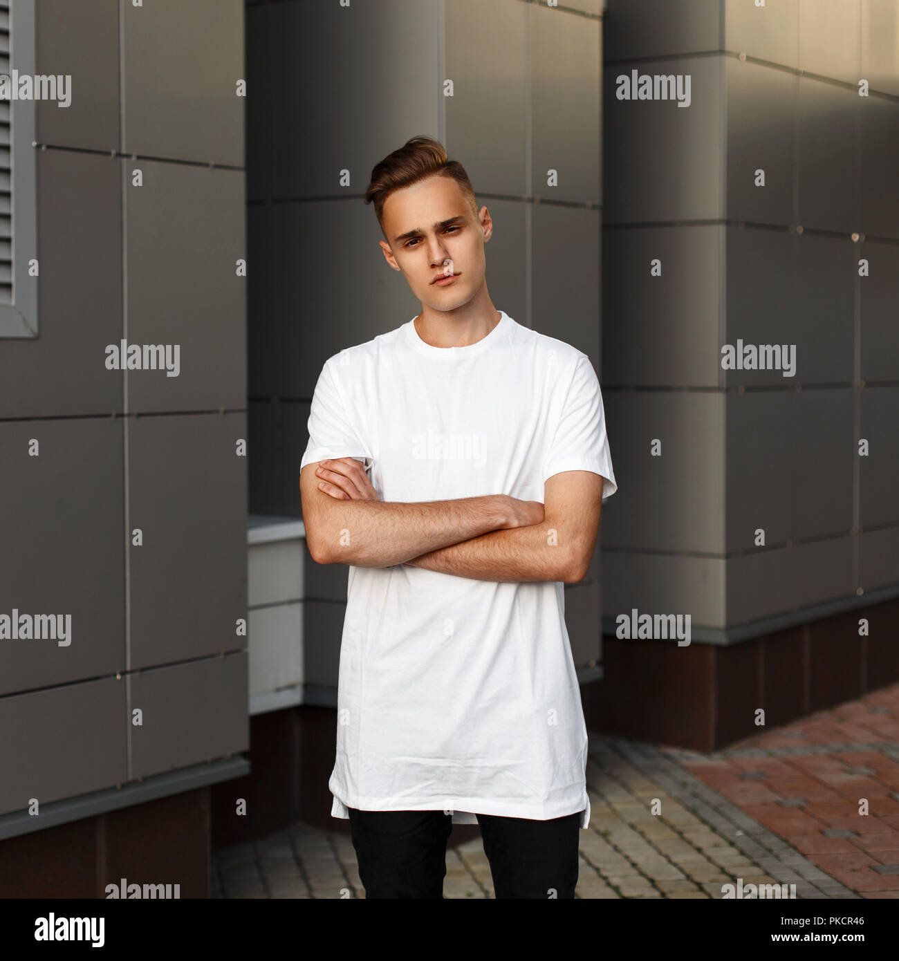 Handsome serious man in a white t-shirt posing near the wall Stock ...