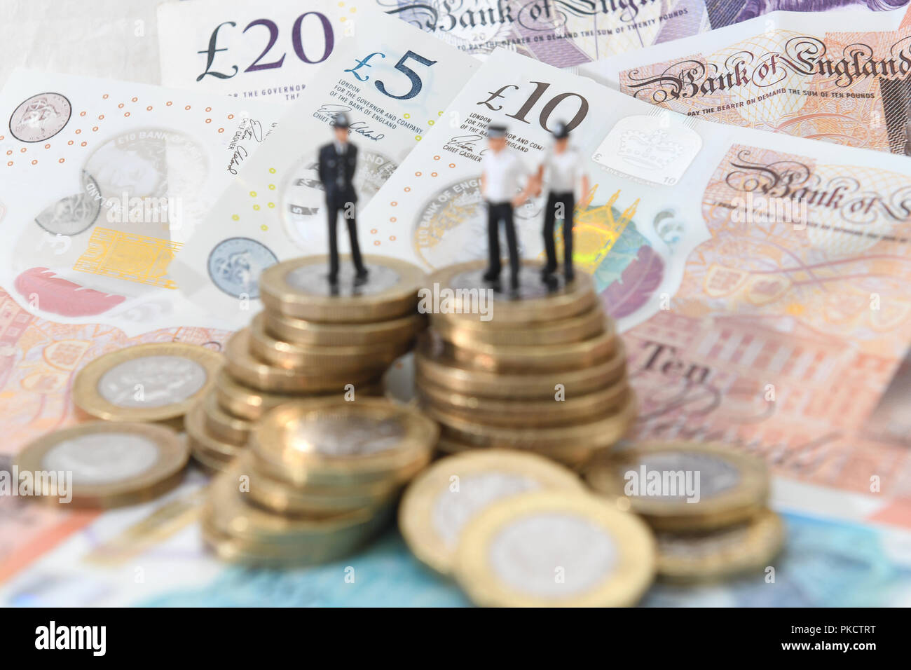 Models of police officers on a pile of coins and bank notes Stock Photo ...