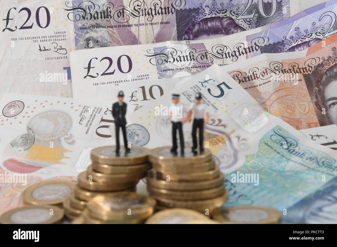 Models of police officers on a pile of coins and bank notes Stock Photo ...