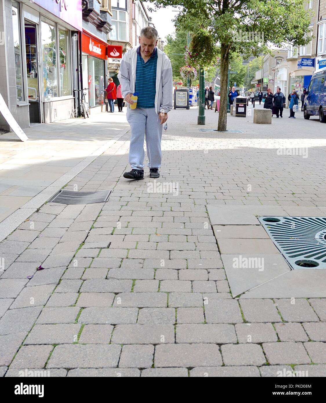 An unkempt man walks along the shopping area in Buxton, Derbyshire ...