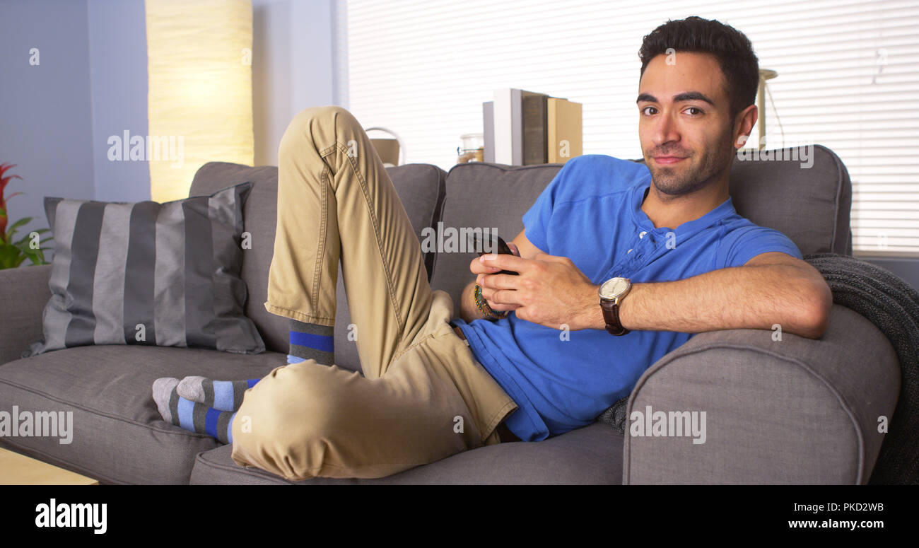 Attractive Mexican man lying on couch Stock Photo - Alamy