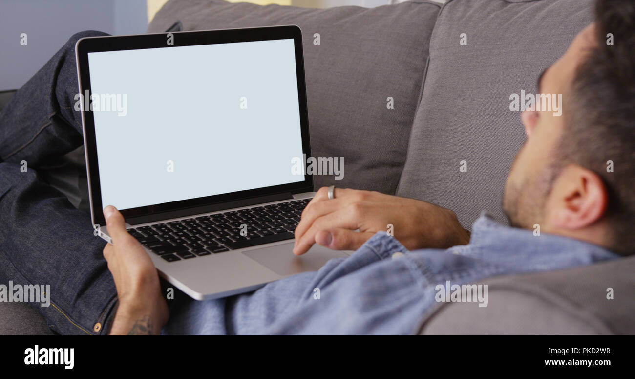 Guy using laptop on couch Stock Photo - Alamy