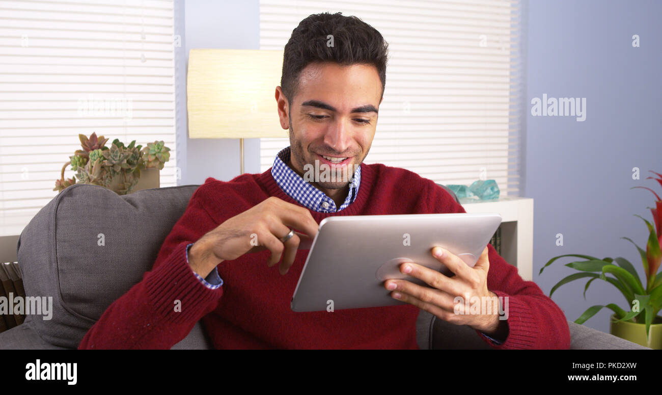 Mexican man using tablet on couch Stock Photo - Alamy