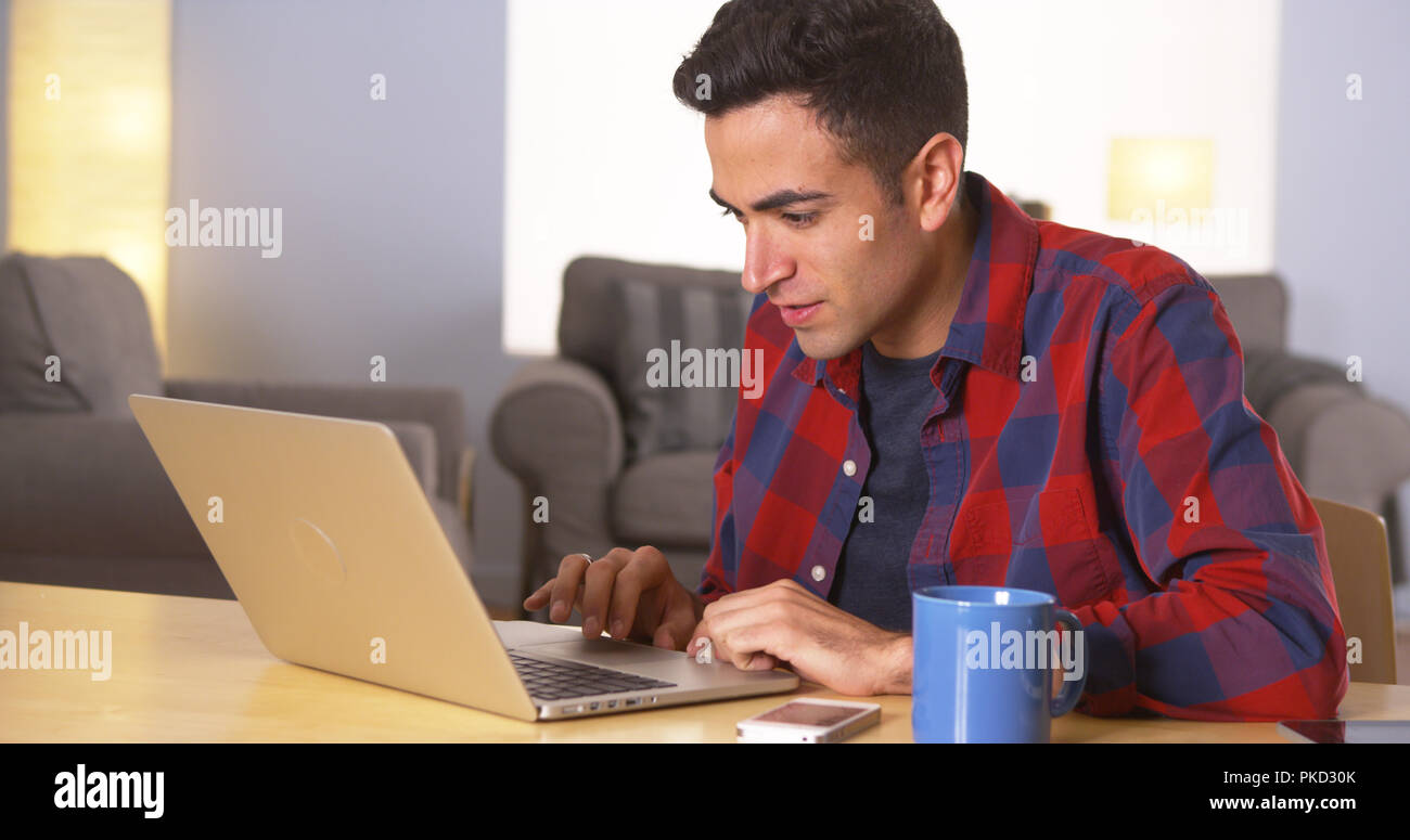 Puerto Rican man working hard at desk with laptop Stock Photo - Alamy