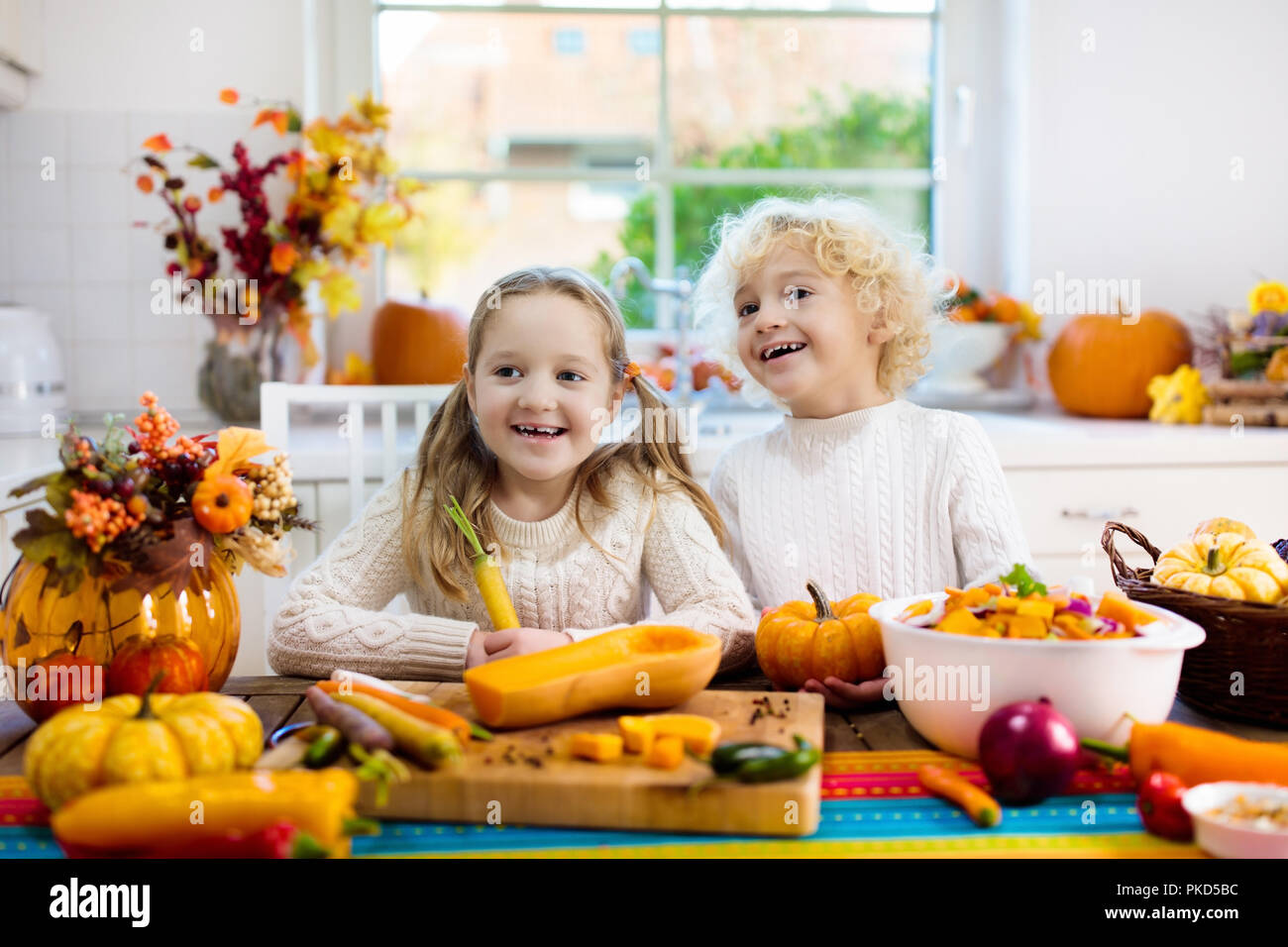 Kids cutting pumpkin, onion and carrot, cooking soup for autumn meal ...