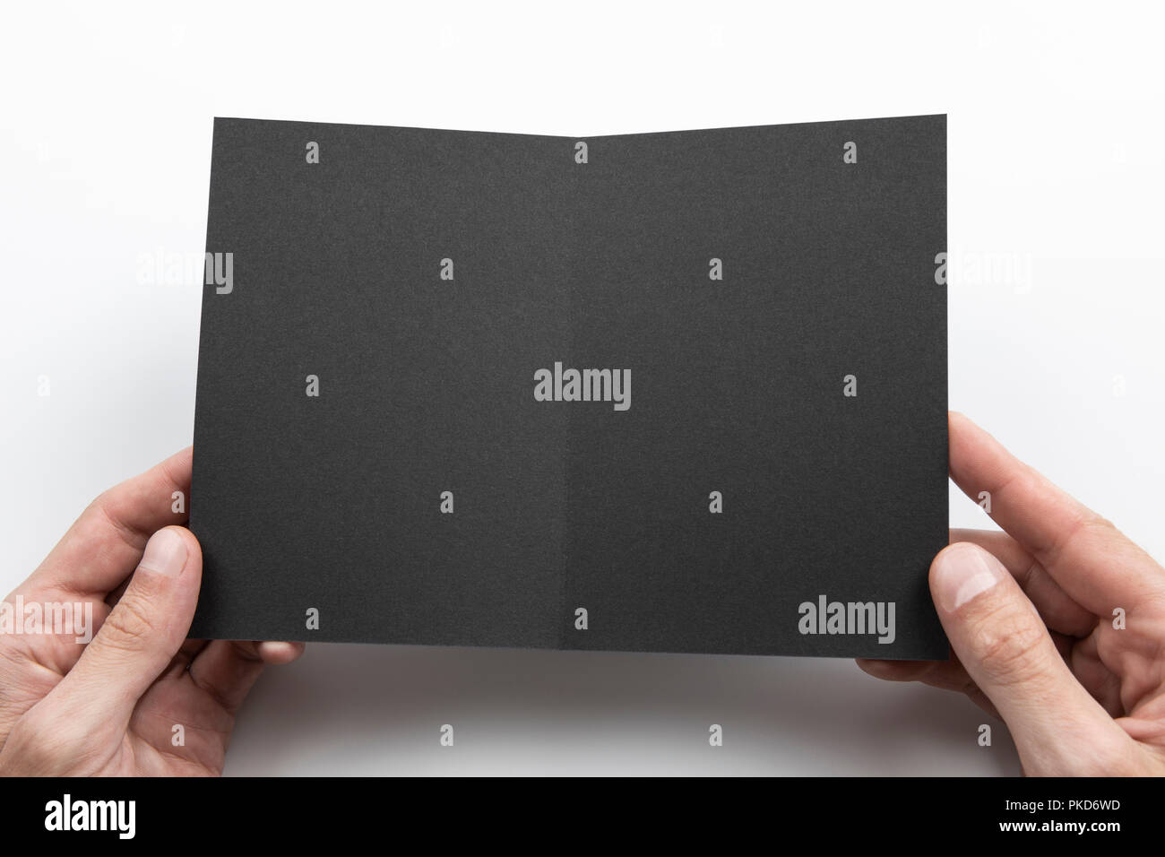 Mens hands holding empty black booklet on white background. View from ...